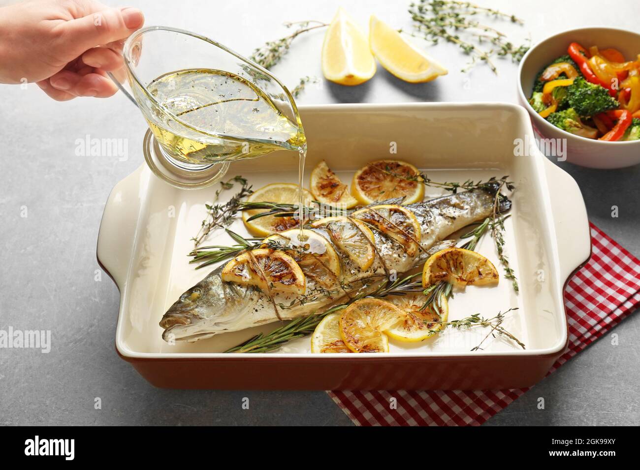 Woman's hand pouring oil onto tasty fish Stock Photo - Alamy