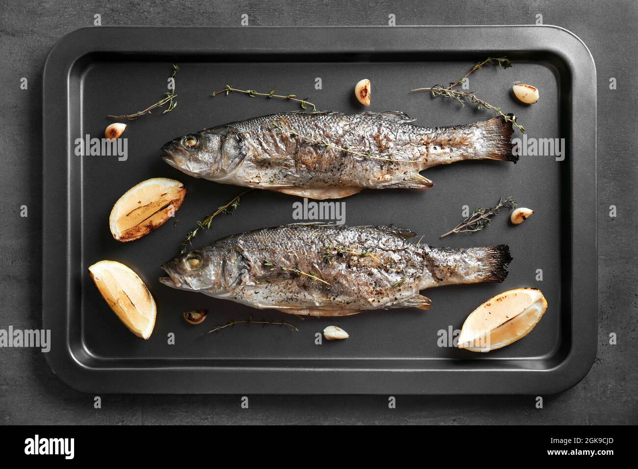 Baking sheet with fried fish on dark background Stock Photo - Alamy