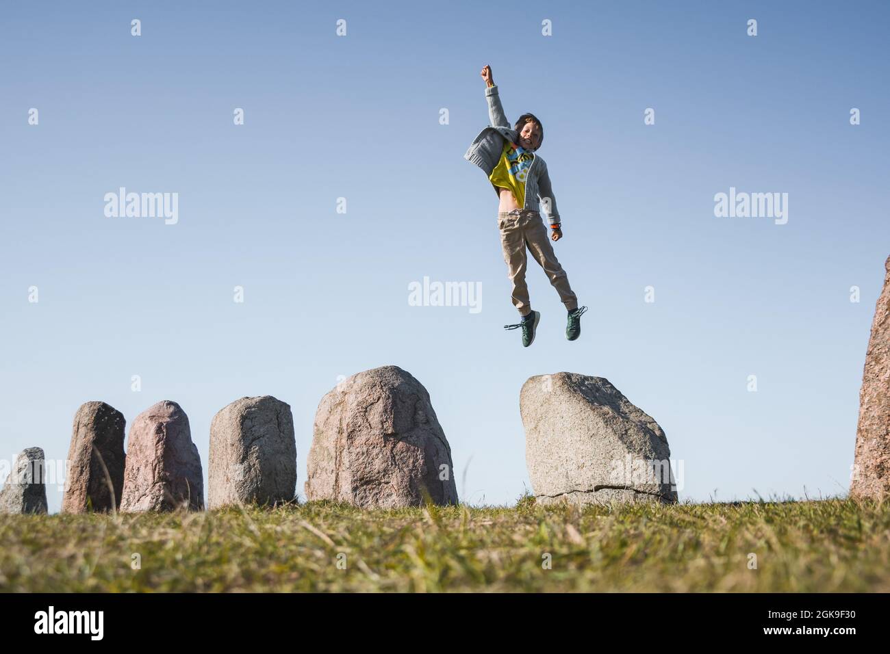 Beautiful shot of a Caucasian boy jumping off a rock in a field Stock ...