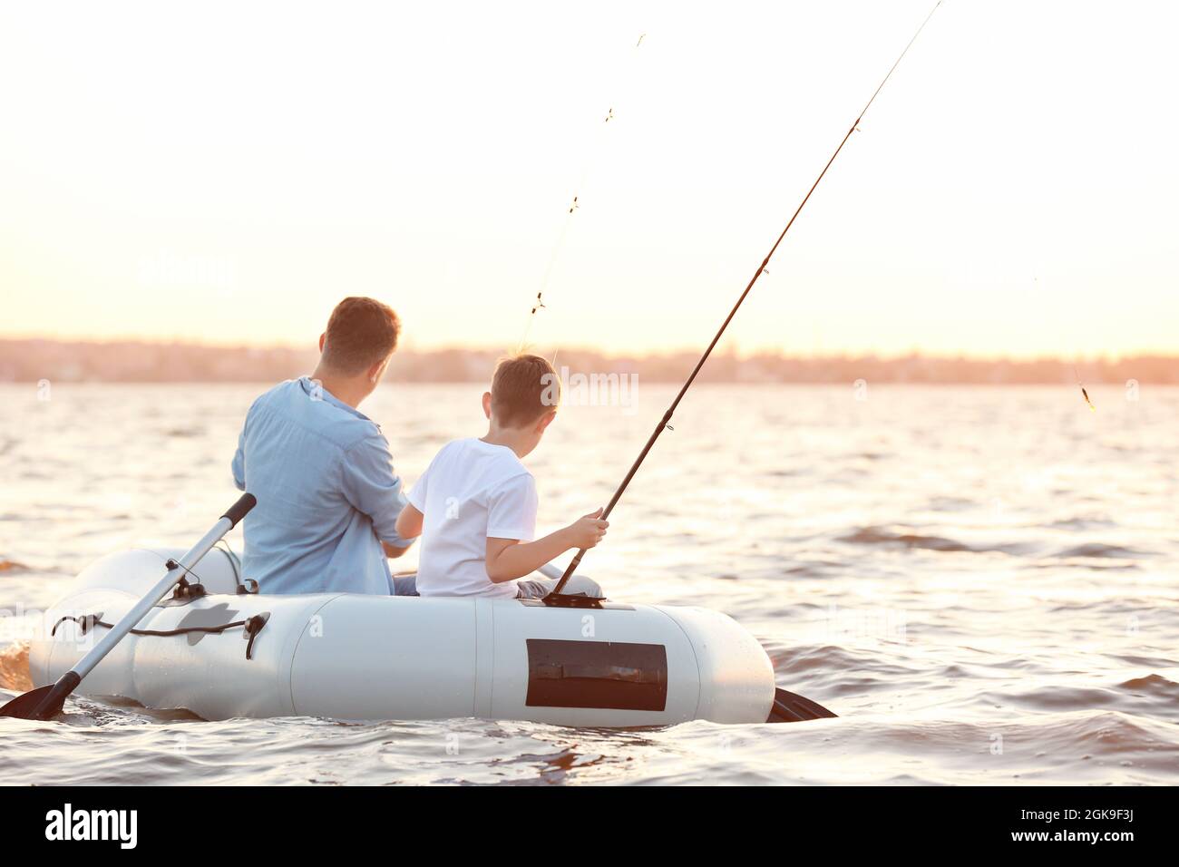 Dad and son fishing from inflatable boat on river Stock Photo - Alamy