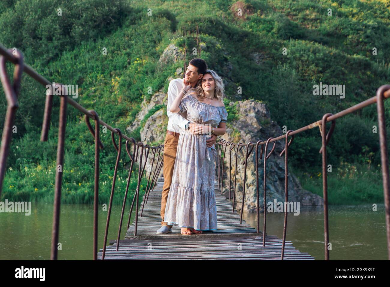 Beautiful young romantic couple standing and hugging on the suspension ...
