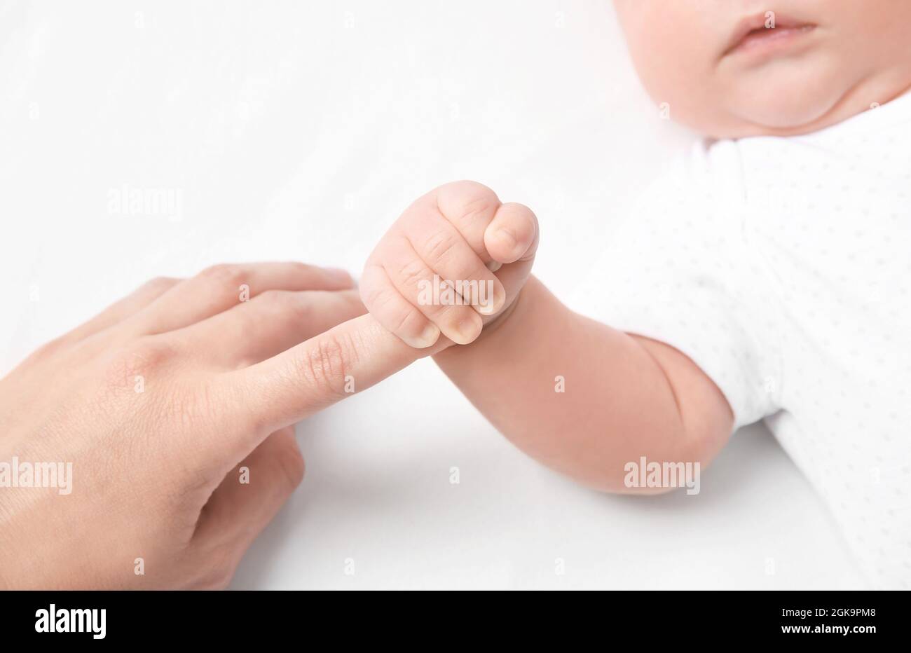Cute little baby holding mother's finger on white background Stock ...