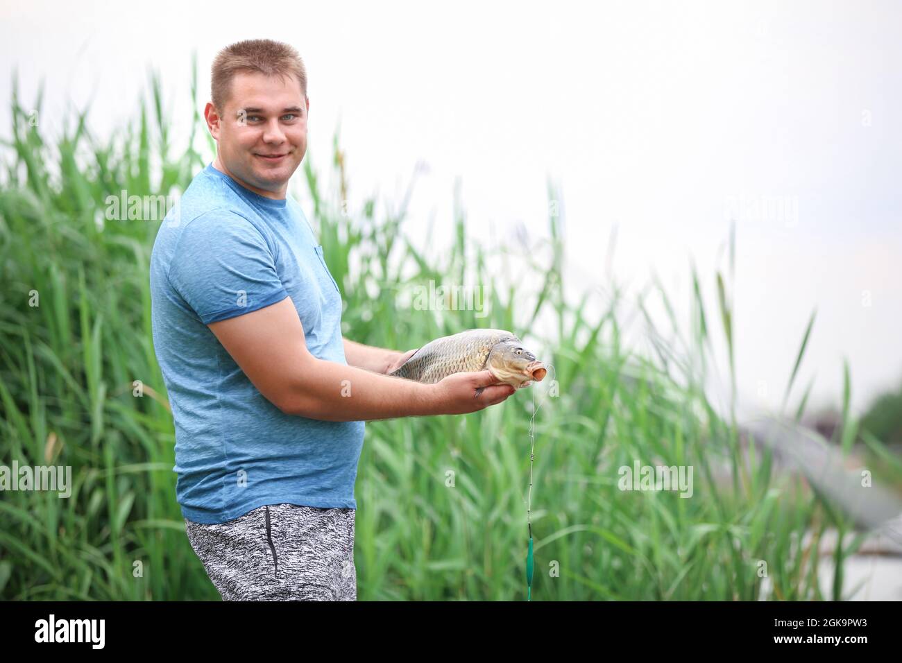 Happy man with freshly caught fish on river bank Stock Photo - Alamy