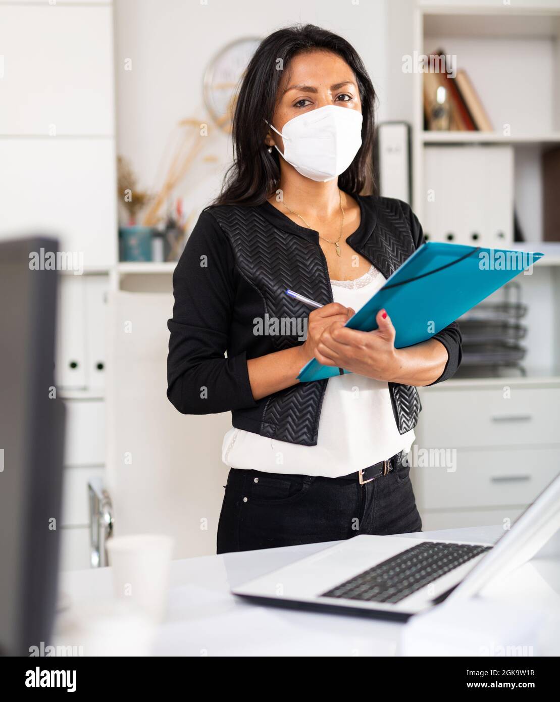 Business woman in face mask writing down tasks in office Stock Photo ...
