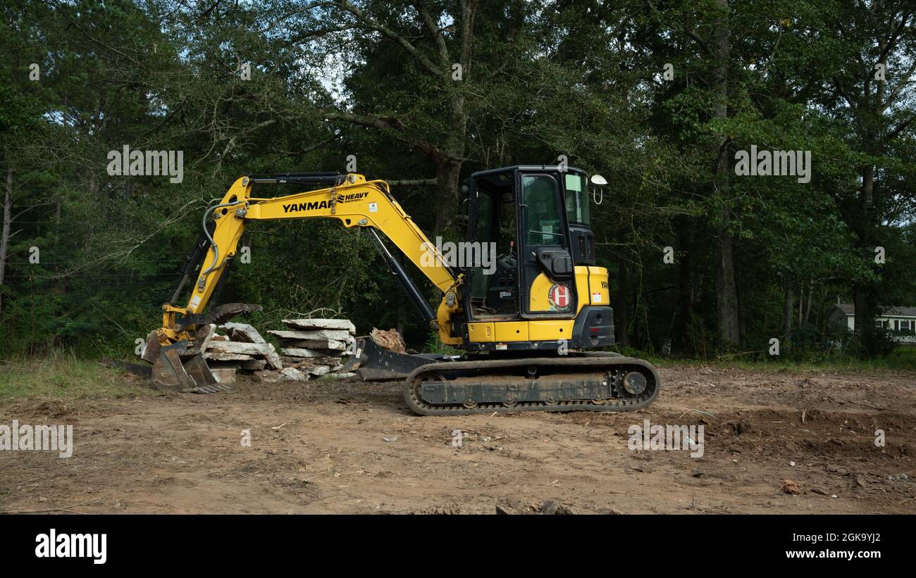 yellow yanmar backhoe demolishing old brick chimney to clear a lot ...