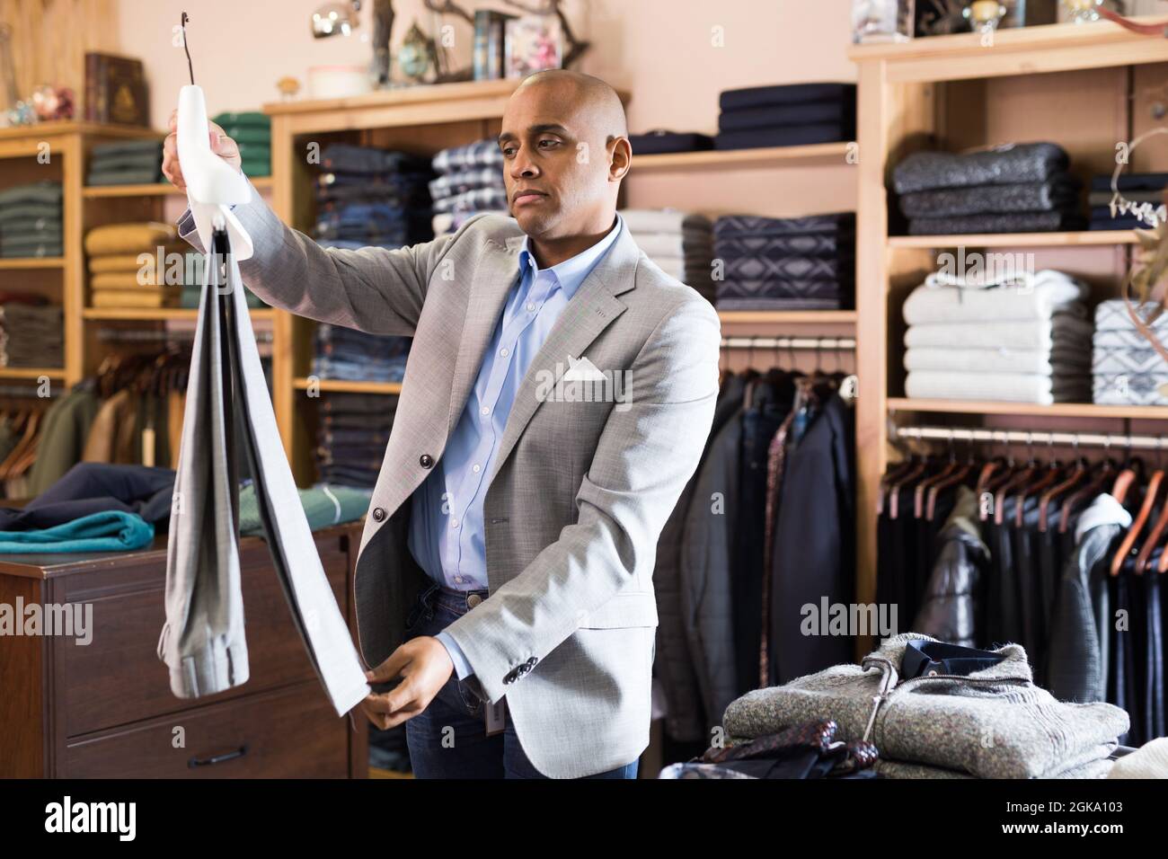 Man choosing suit jacket in clothing store Stock Photo - Alamy
