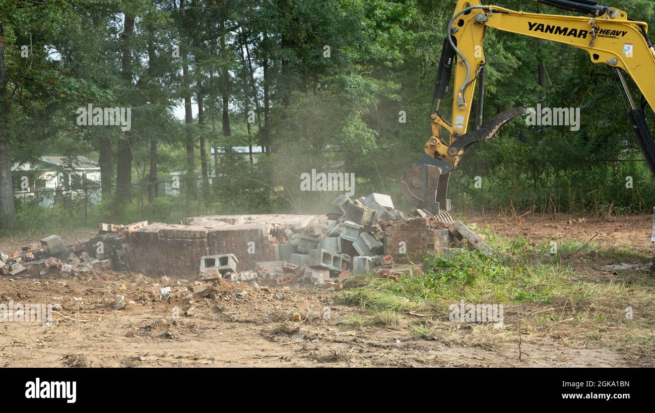 yellow yanmar backhoe demolishing old brick chimney to clear a lot ...
