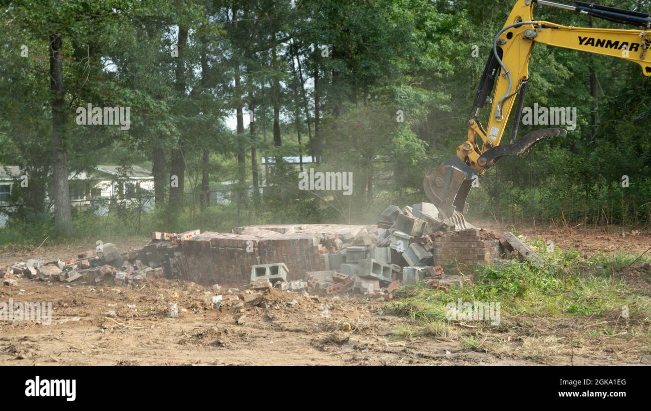 yellow yanmar backhoe demolishing old brick chimney to clear a lot ...