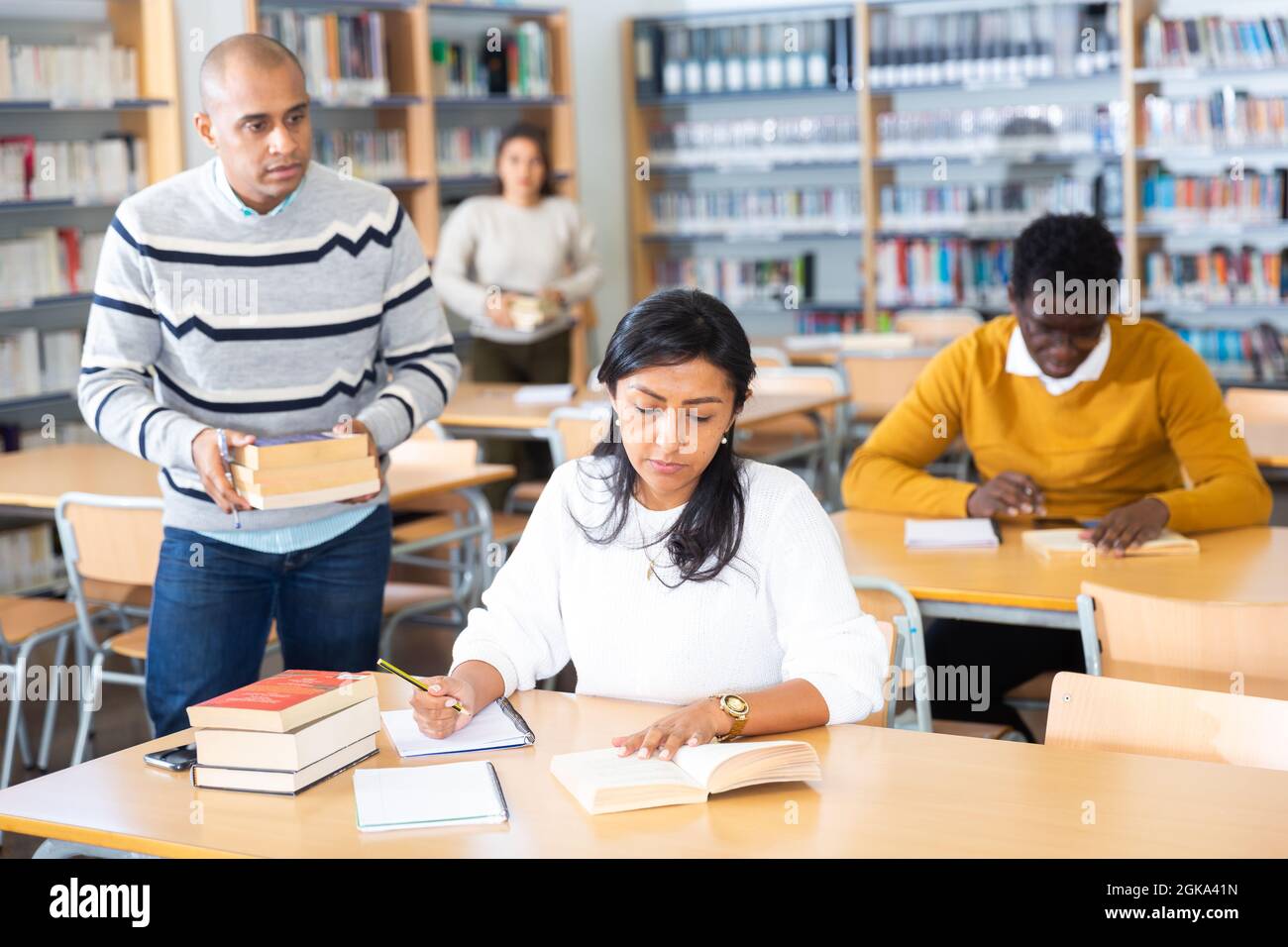 Latin american woman reading books and making notes in library Stock ...