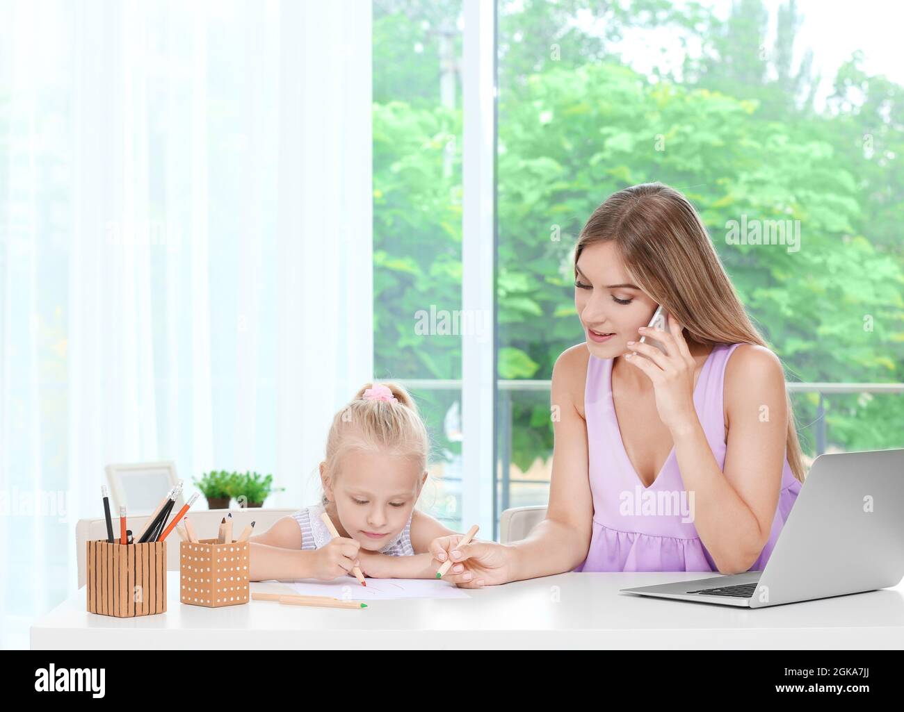 Busy young woman with her daughter at home Stock Photo - Alamy