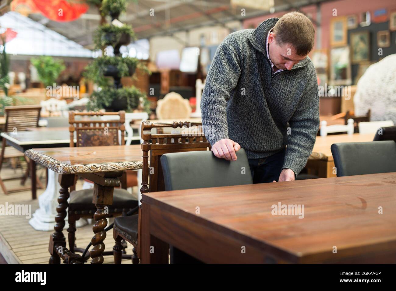 Man chooses wooden table in furniture store Stock Photo - Alamy