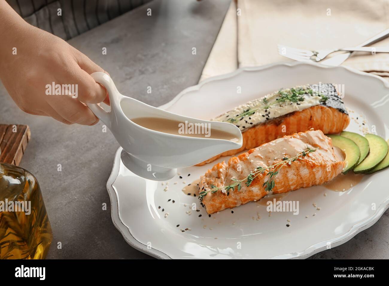 Woman pouring fish sauce onto plate with delicious salmon Stock Photo ...