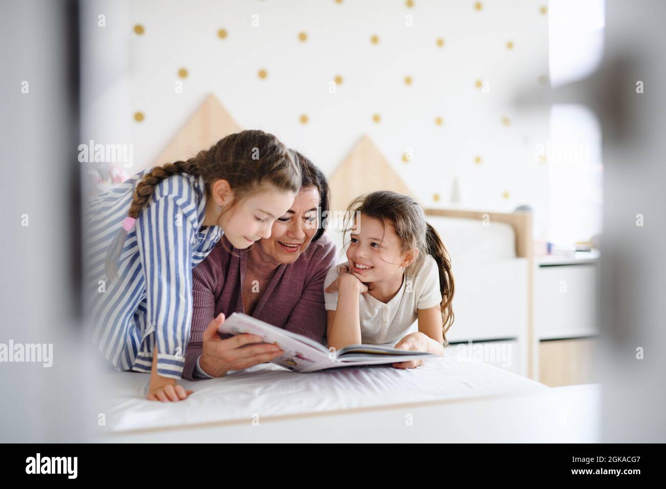 Happy small girls with senior grandmother indoors in bedroom at home ...