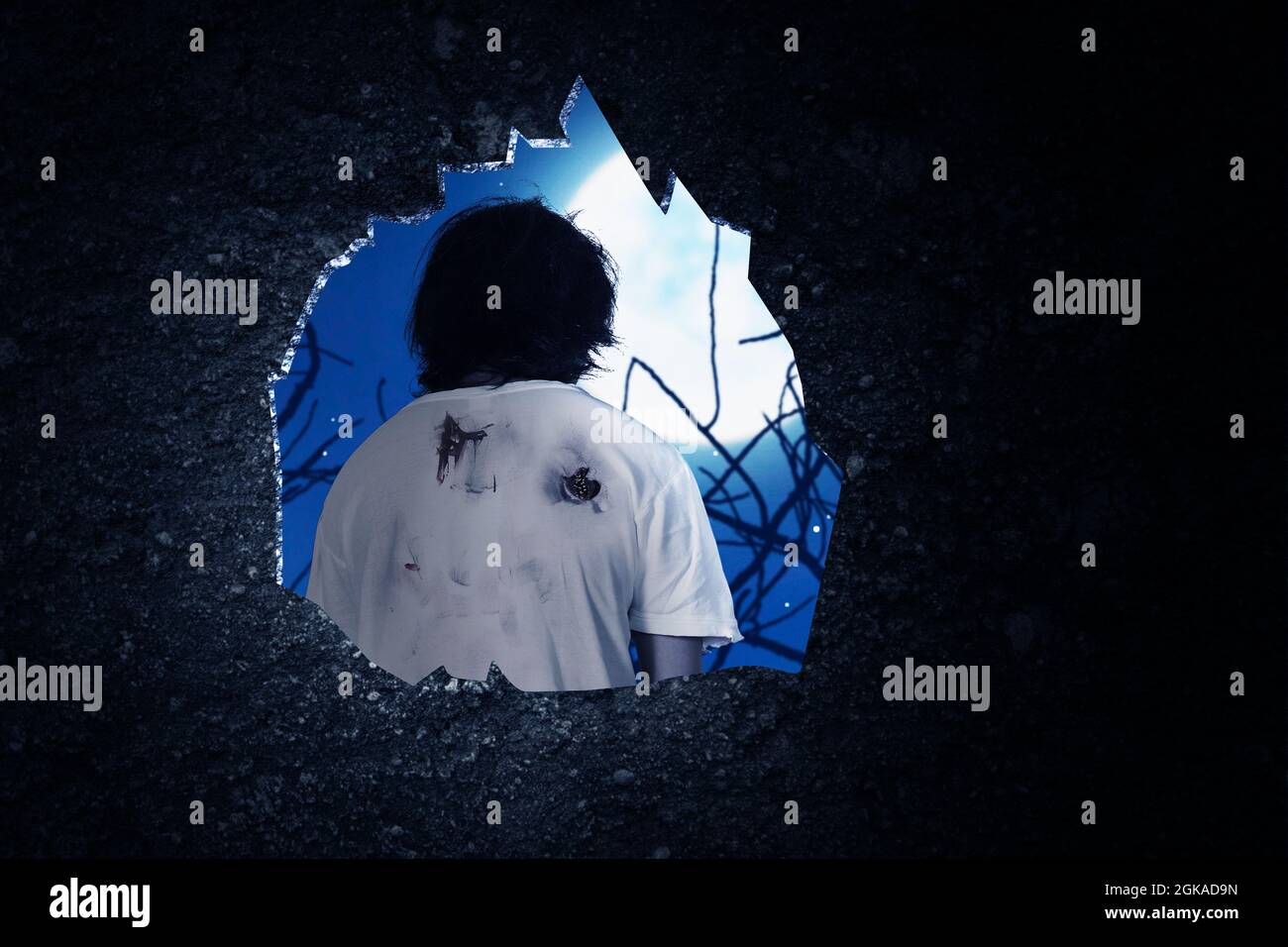 Wall hole with a scary zombie standing with night scene background ...