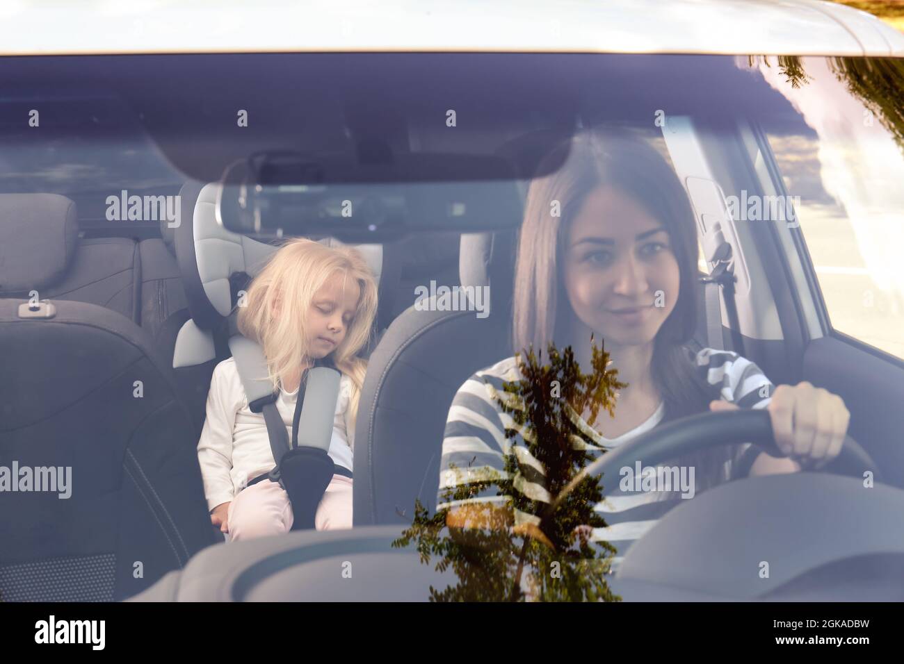 Young woman driving car with small girl in safety seat Stock Photo - Alamy