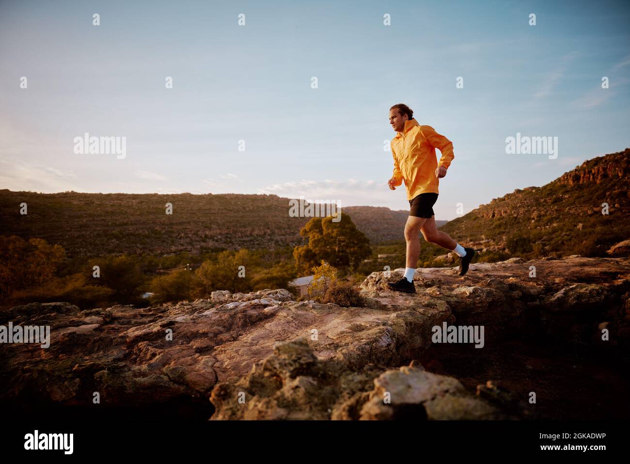 Fitness male running through rocky mountain path Stock Photo - Alamy