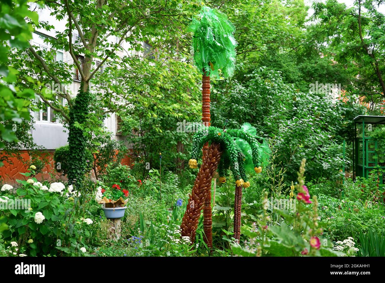 Palm trees made from recycled plastic bottles in green garden near ...