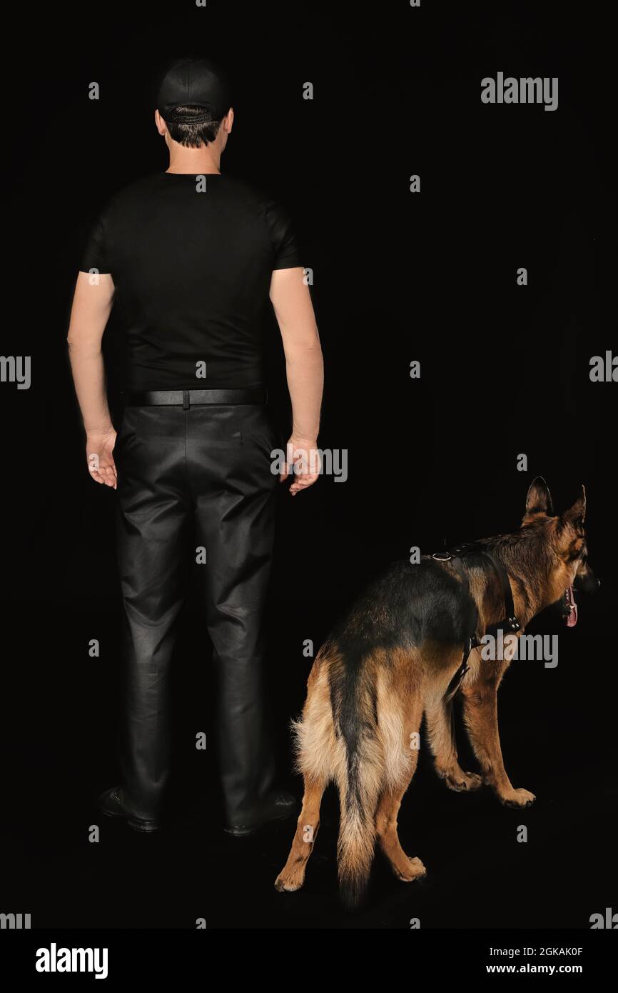 Security guard with dog on black background Stock Photo - Alamy