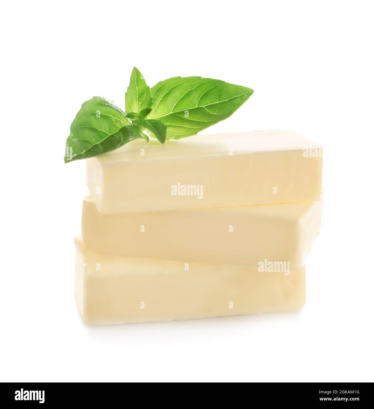 Cut block of butter with fresh basil leaves isolated on white Stock ...