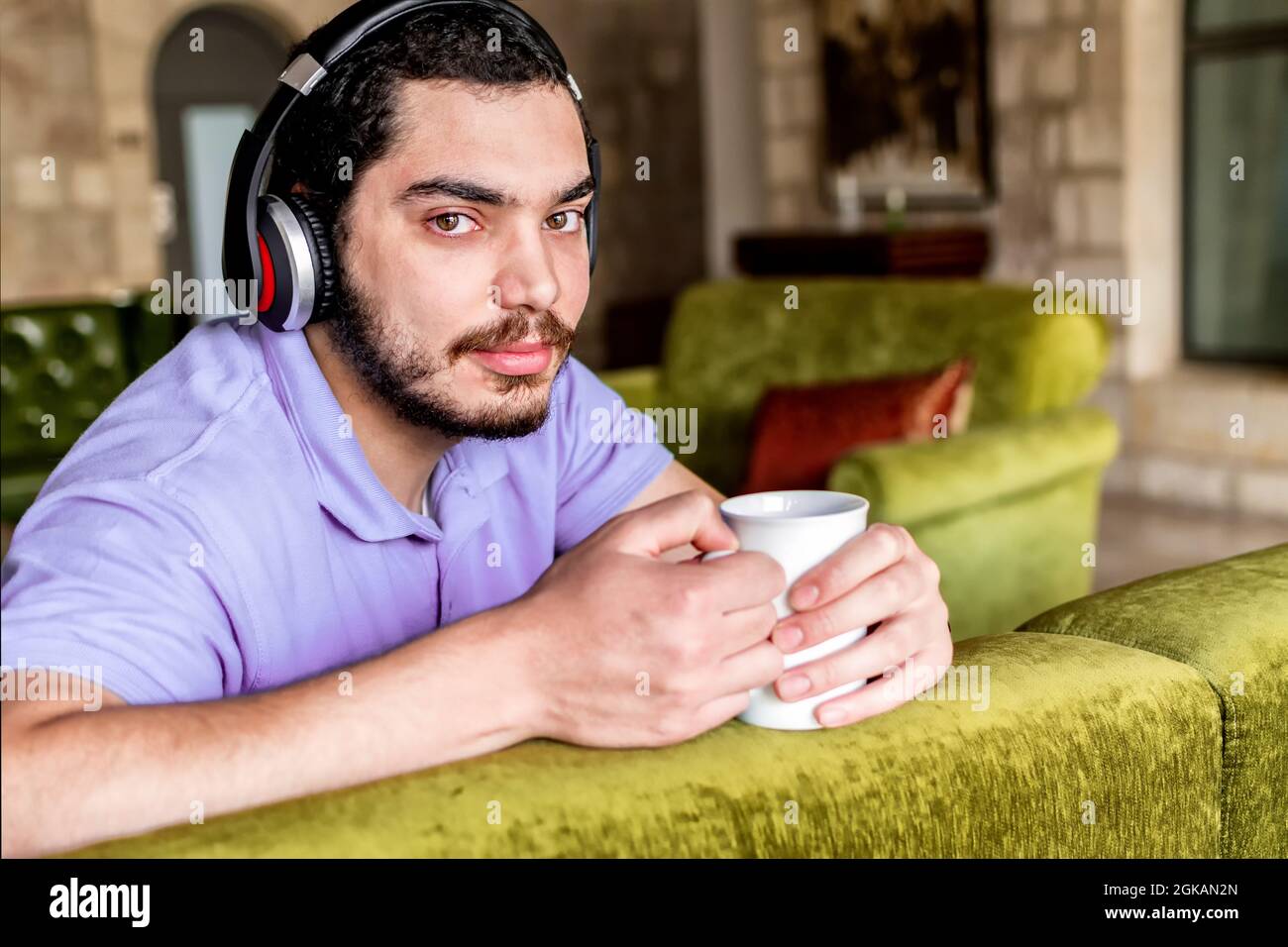 Bearded Israeli man with headphones drinking coffee while sitting on a ...