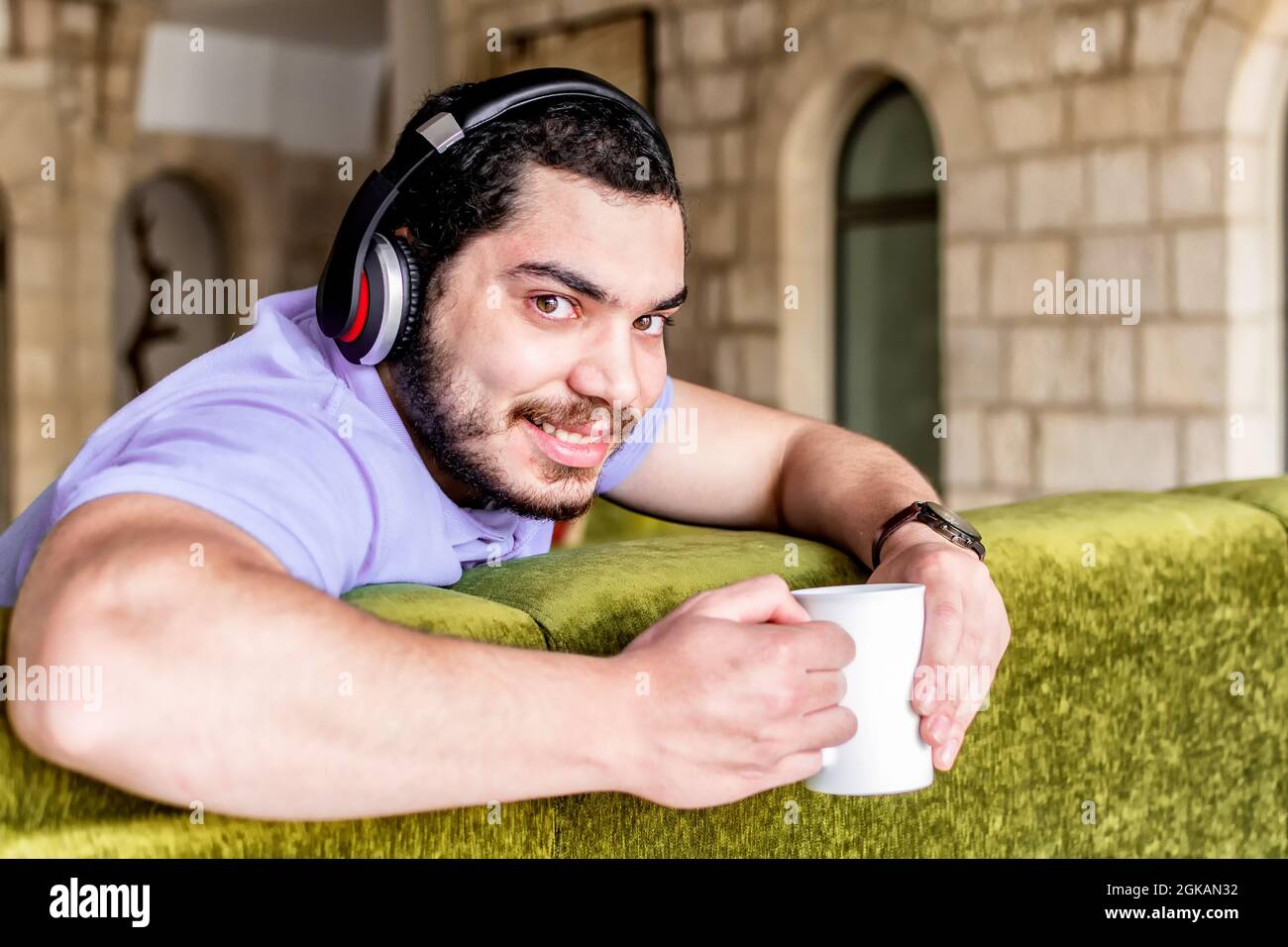Bearded Israeli man with headphones drinking coffee while sitting on a ...