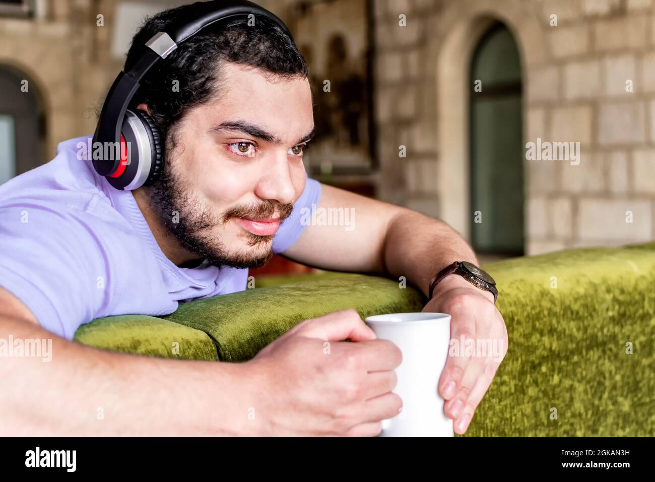 Bearded Israeli man with headphones drinking coffee while sitting on a ...