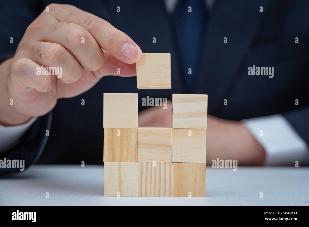 The hands of a male businessman who is stacking wooden blocks. Business ...