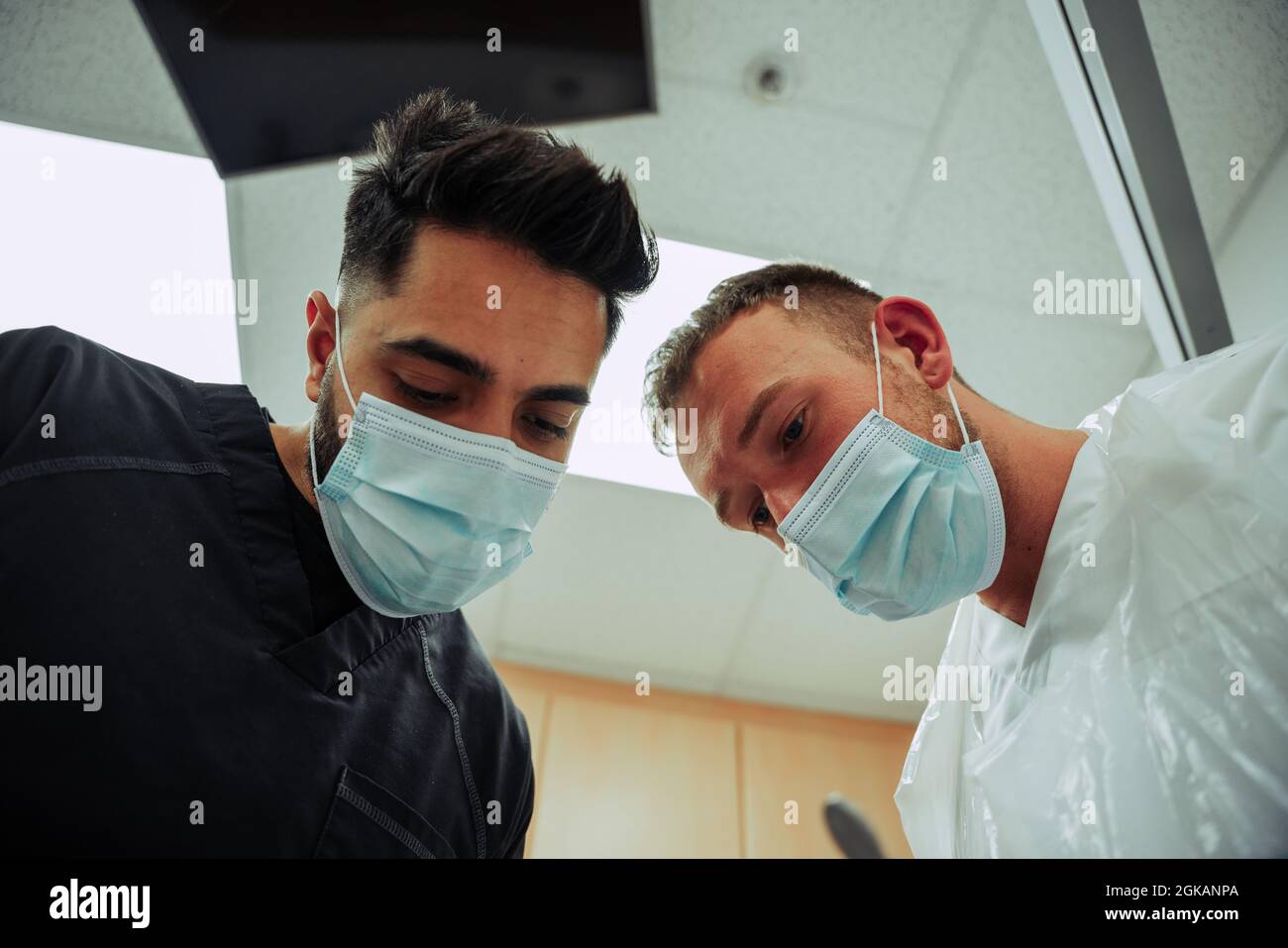 Two caucasian male doctors wearing surgical gear looking down on ...