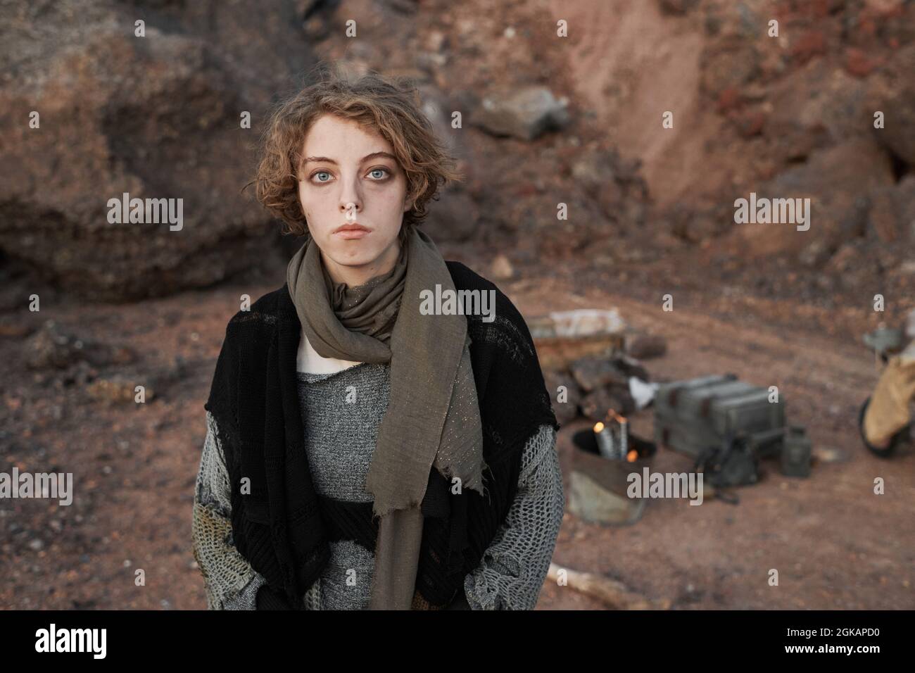 Portrait of young homeless woman in torn clothes looking at camera ...