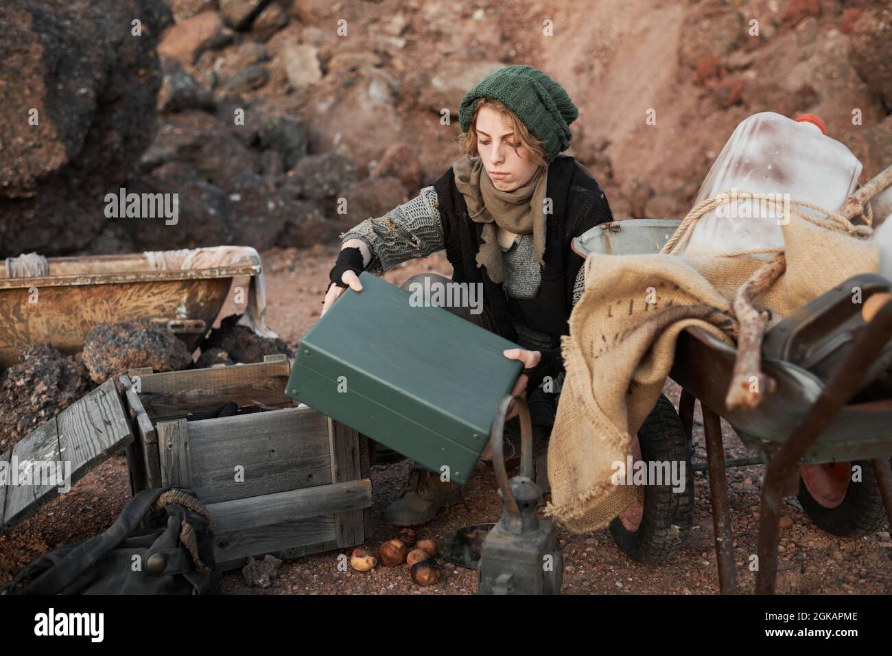 Young homeless woman in torn clothes taking the box out among her ...