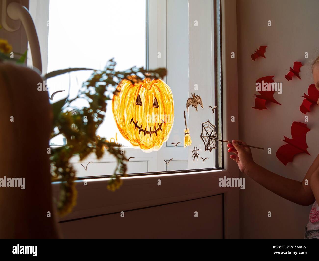 Child painting pumpkin on window preparing celebrate Halloween. Little ...