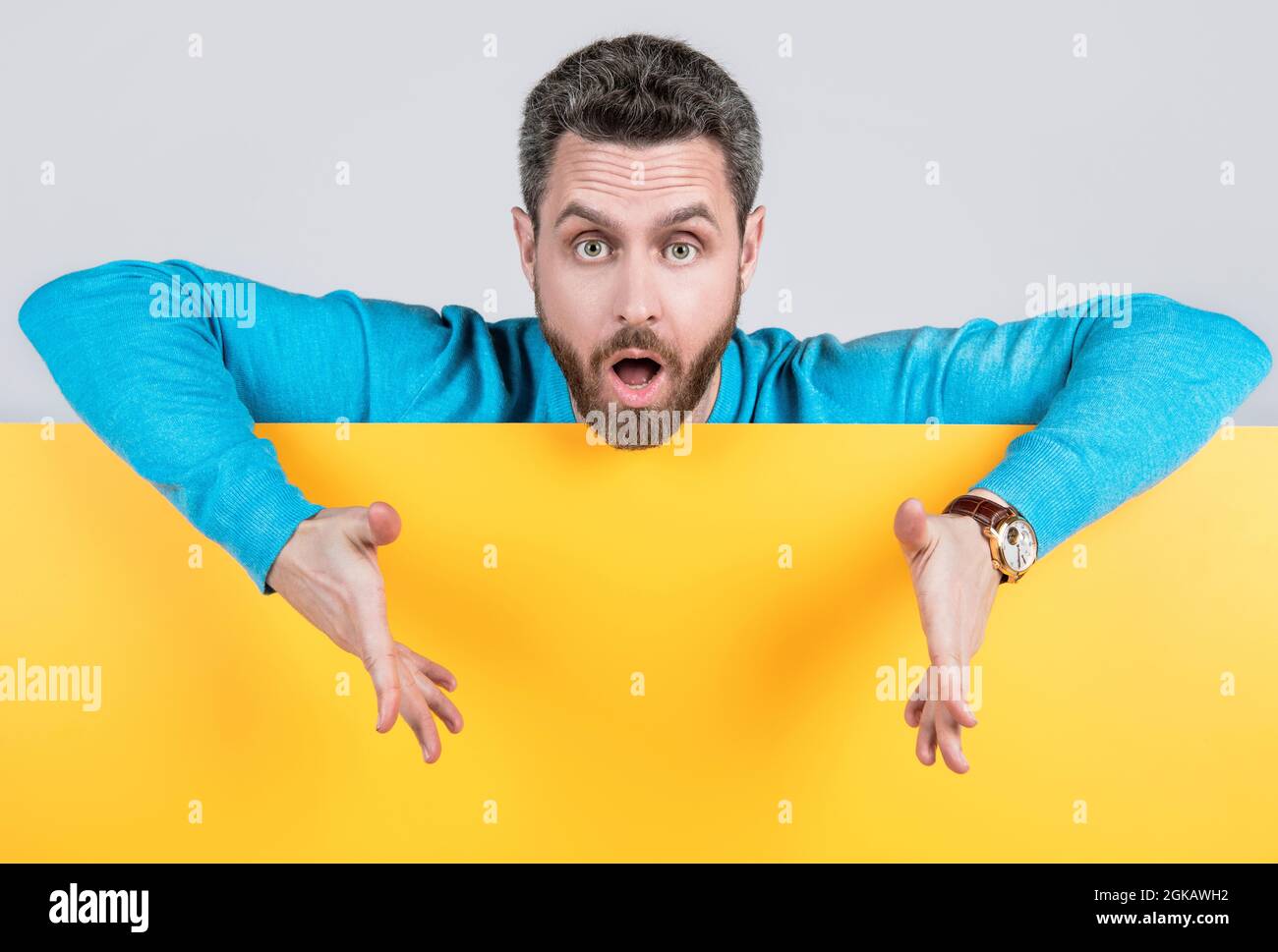 surprised man behind blank paper banner with copy space for information ...
