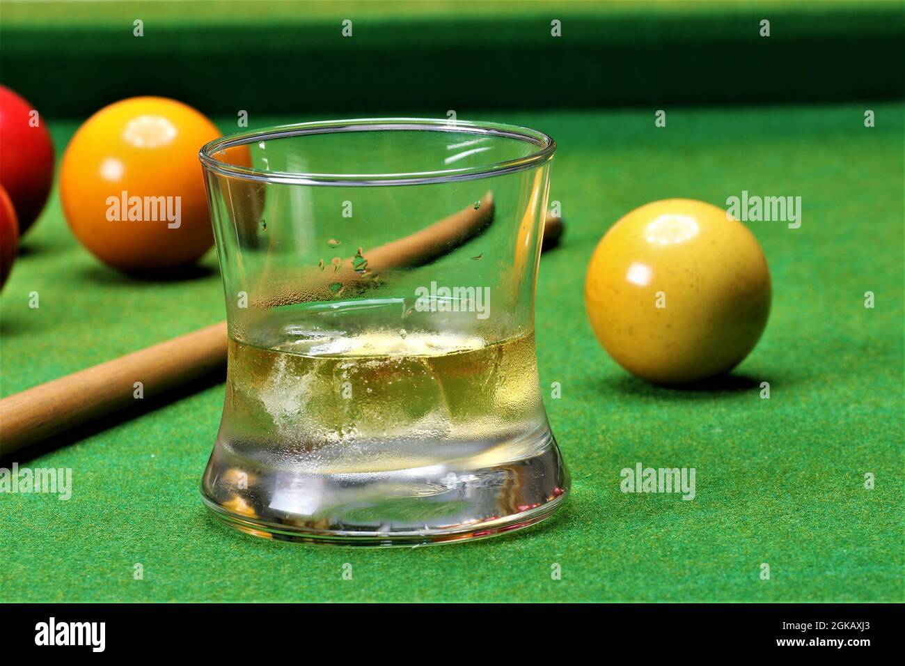 Close-up shot of a glass of whiskey on the pool table with a cue and ...