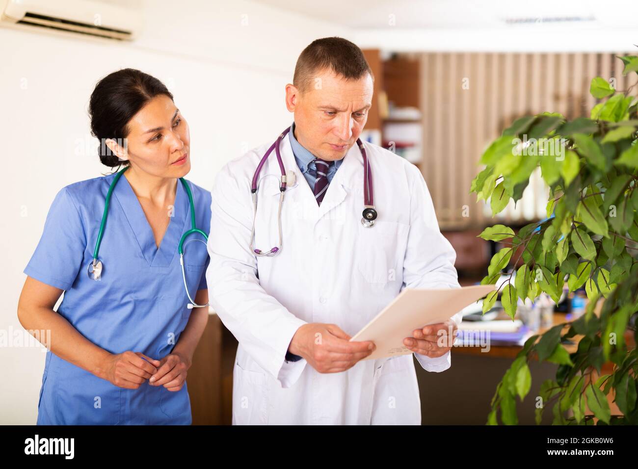 Experienced doctor advising female colleague about diagnosis of patient ...