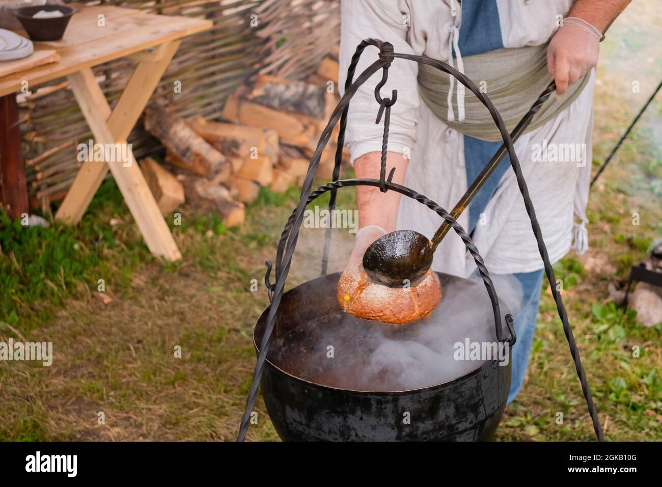 Preparing soup in hanging pot over open fire - camping concept Stock ...