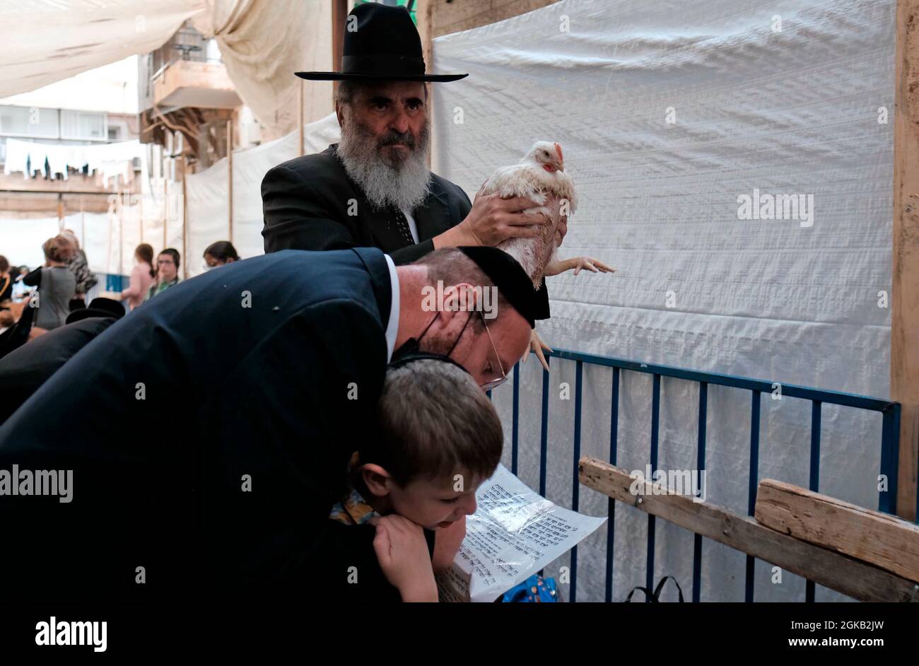 An ultra-Orthodox Jewish man swings a chicken over the head of a member ...