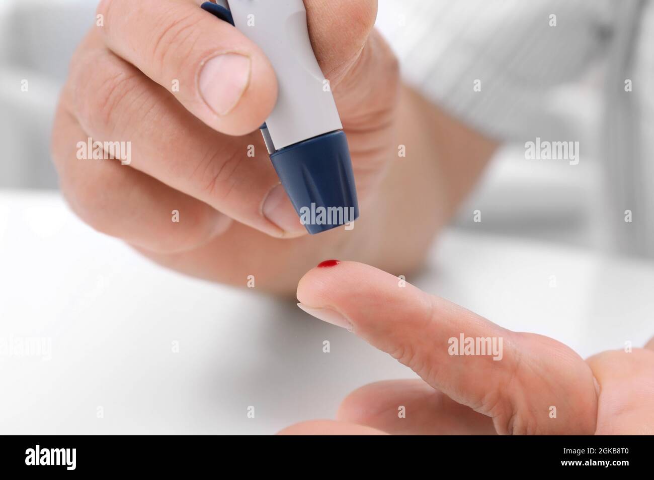 Man taking blood sample with lancet pen indoors Stock Photo - Alamy