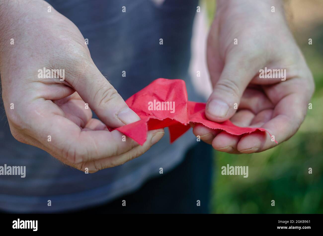 A man nervously tears a piece of red paper. Hands holding a wet Stock ...