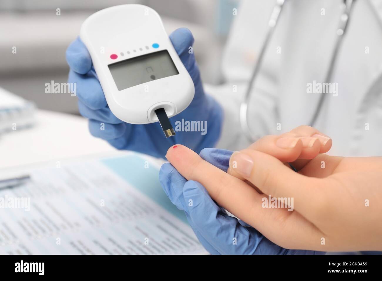 Medical technician in latex gloves testing patient's glucose level with ...