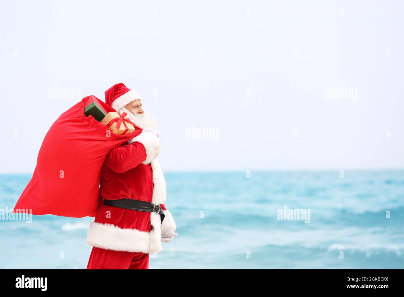 Authentic Santa Claus with big red bag full of gifts on sea background ...