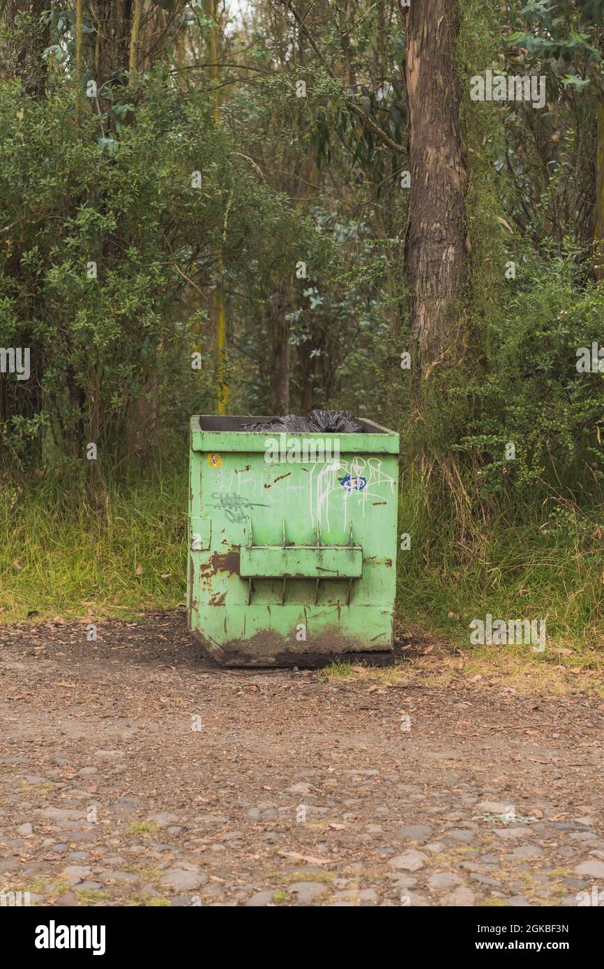 Vertical shot of a garbage container in a park with trees in a forest ...