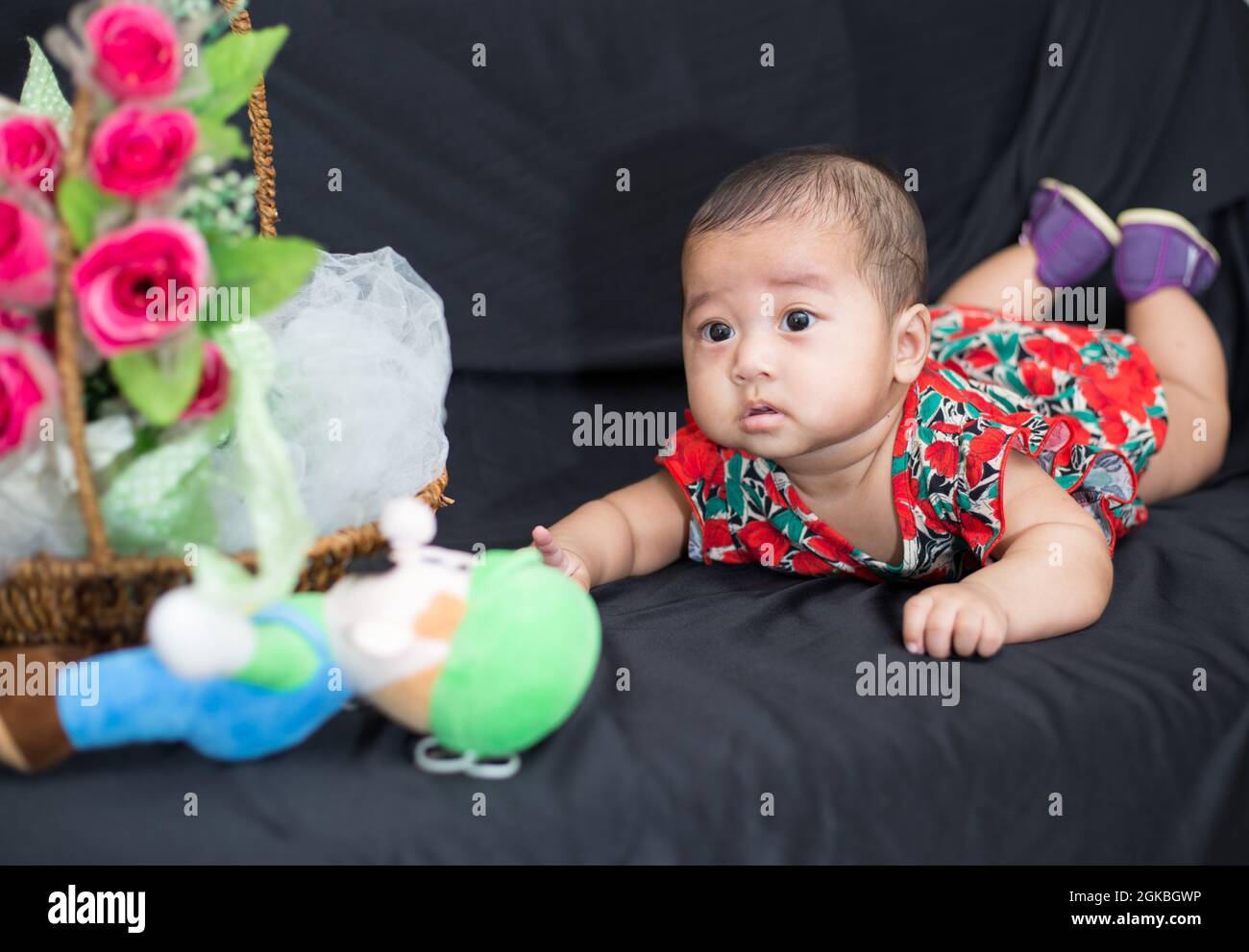 Adorable Malaysian baby lying on the couch with toys Stock Photo - Alamy