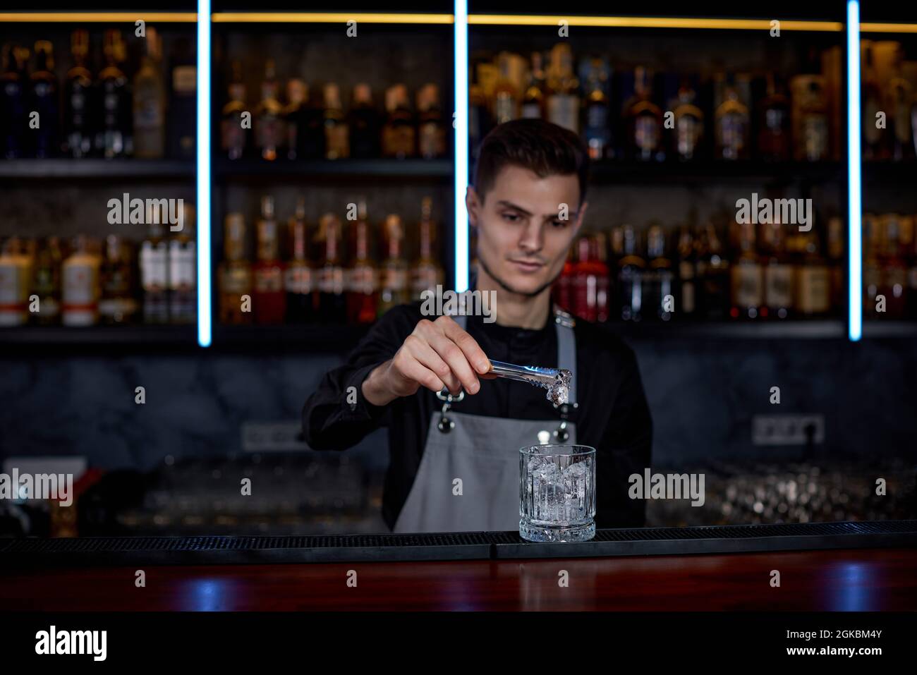 Barman puts the ice cubes into a glass Stock Photo - Alamy