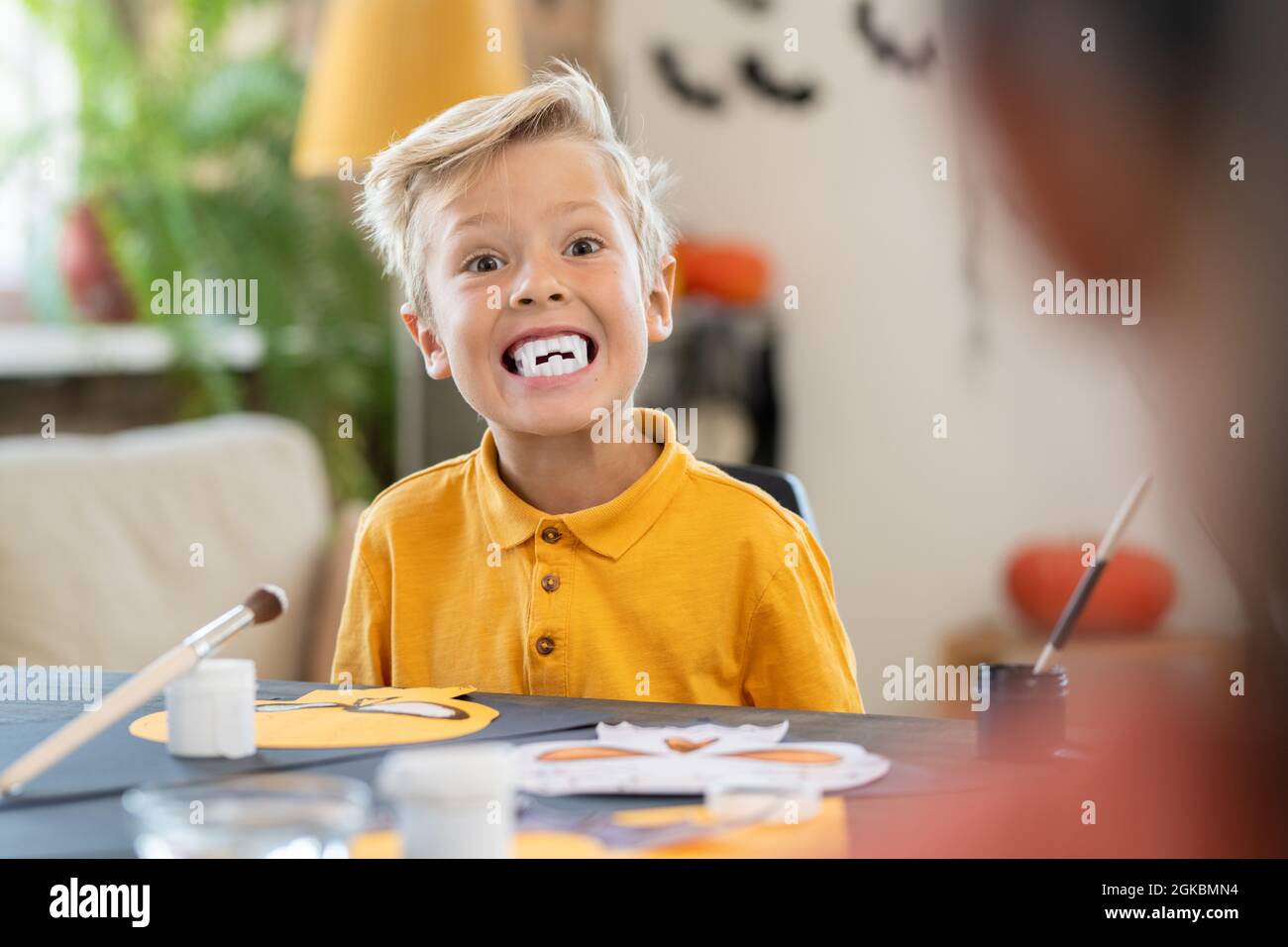 Spooky boy with white fangs looking at camera with frightening ...