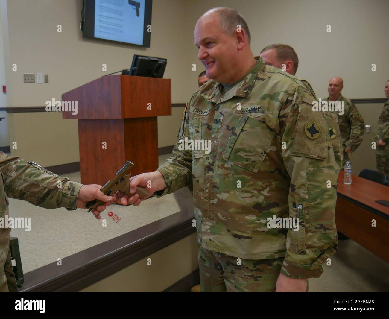 Col. Thomas Crosby, 184th Sustainment Command, is handed the M17 pistol ...