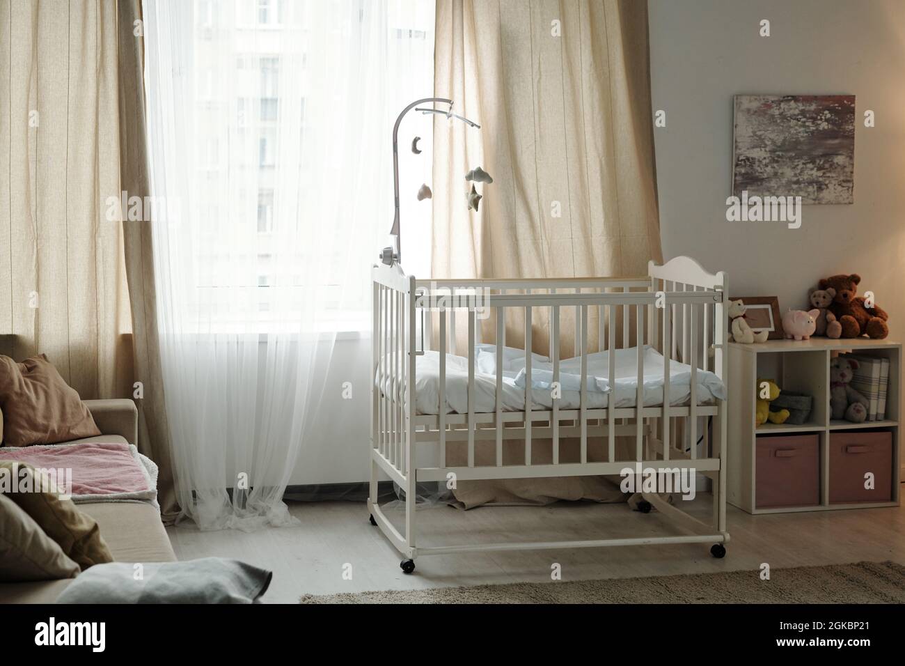 Part of cozy bedroom of newborn baby with crib standing by large window ...