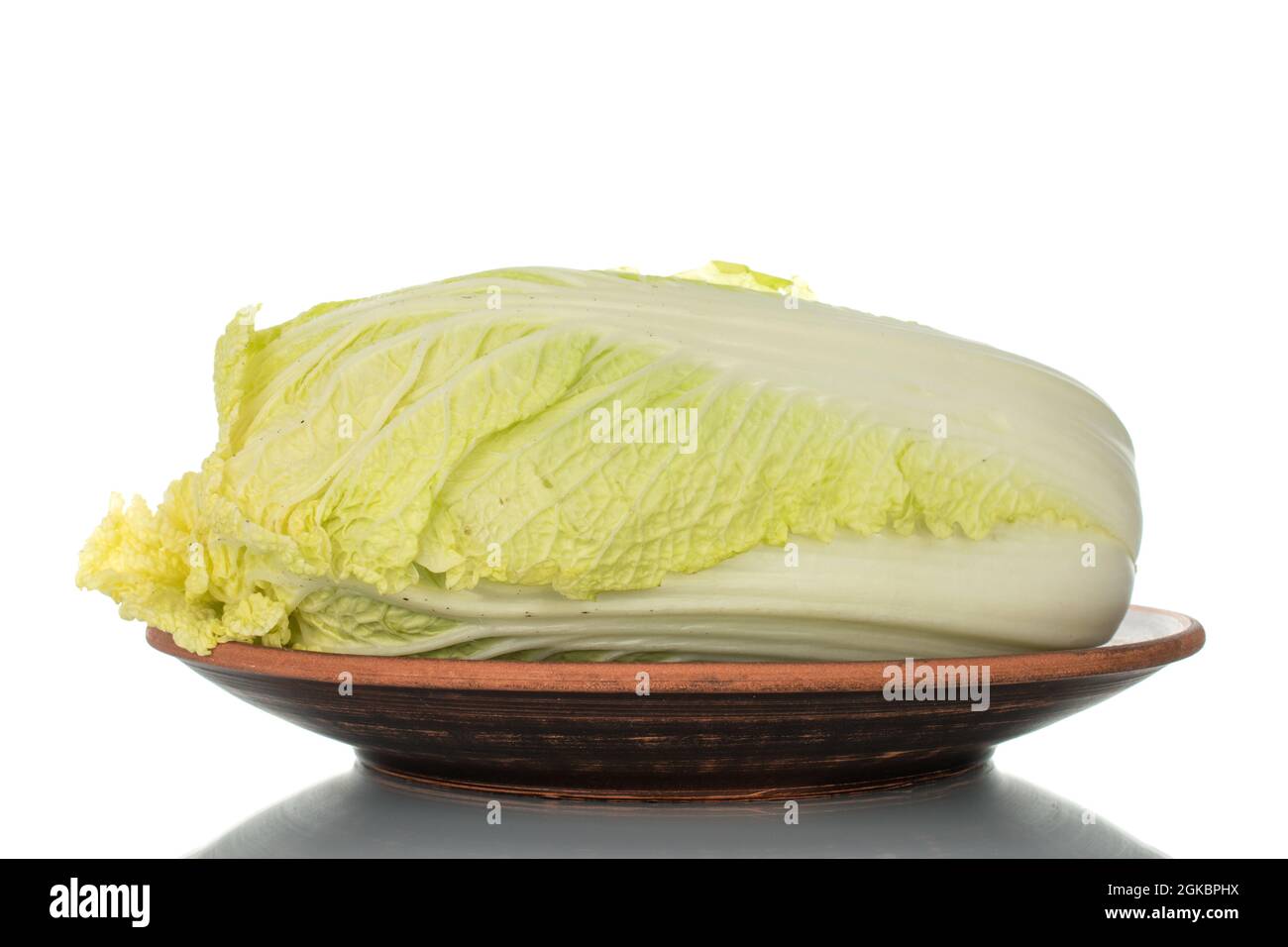 One organic Chinese cabbage on a clay dish, close-up, isolated on white ...