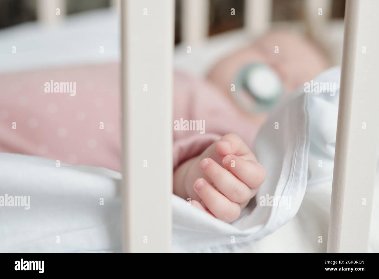 Small fingers and hand of tired baby girl sleeping on white linens in ...