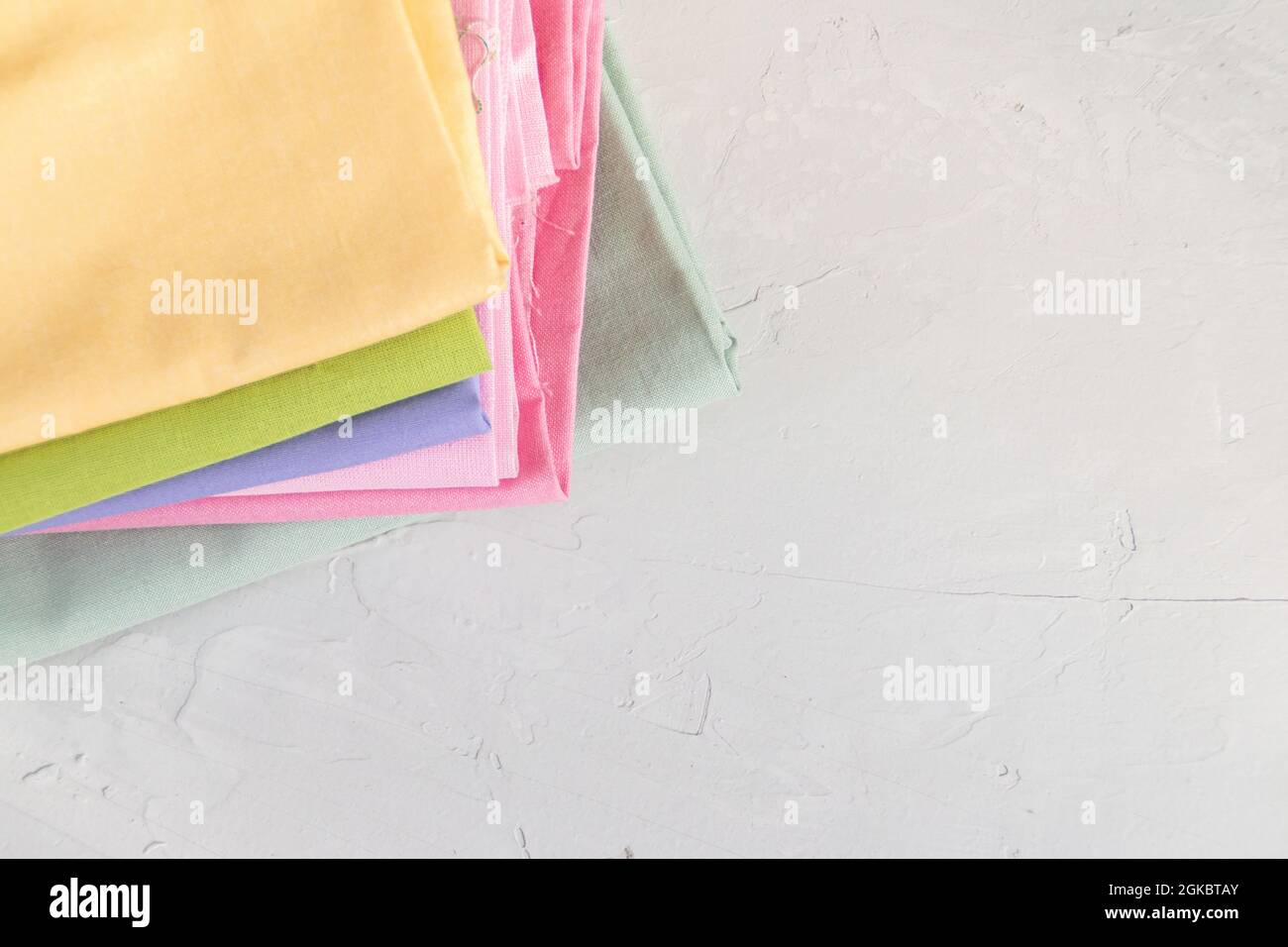Stack of colorful cotton fabric against grey background, slow fashion ...