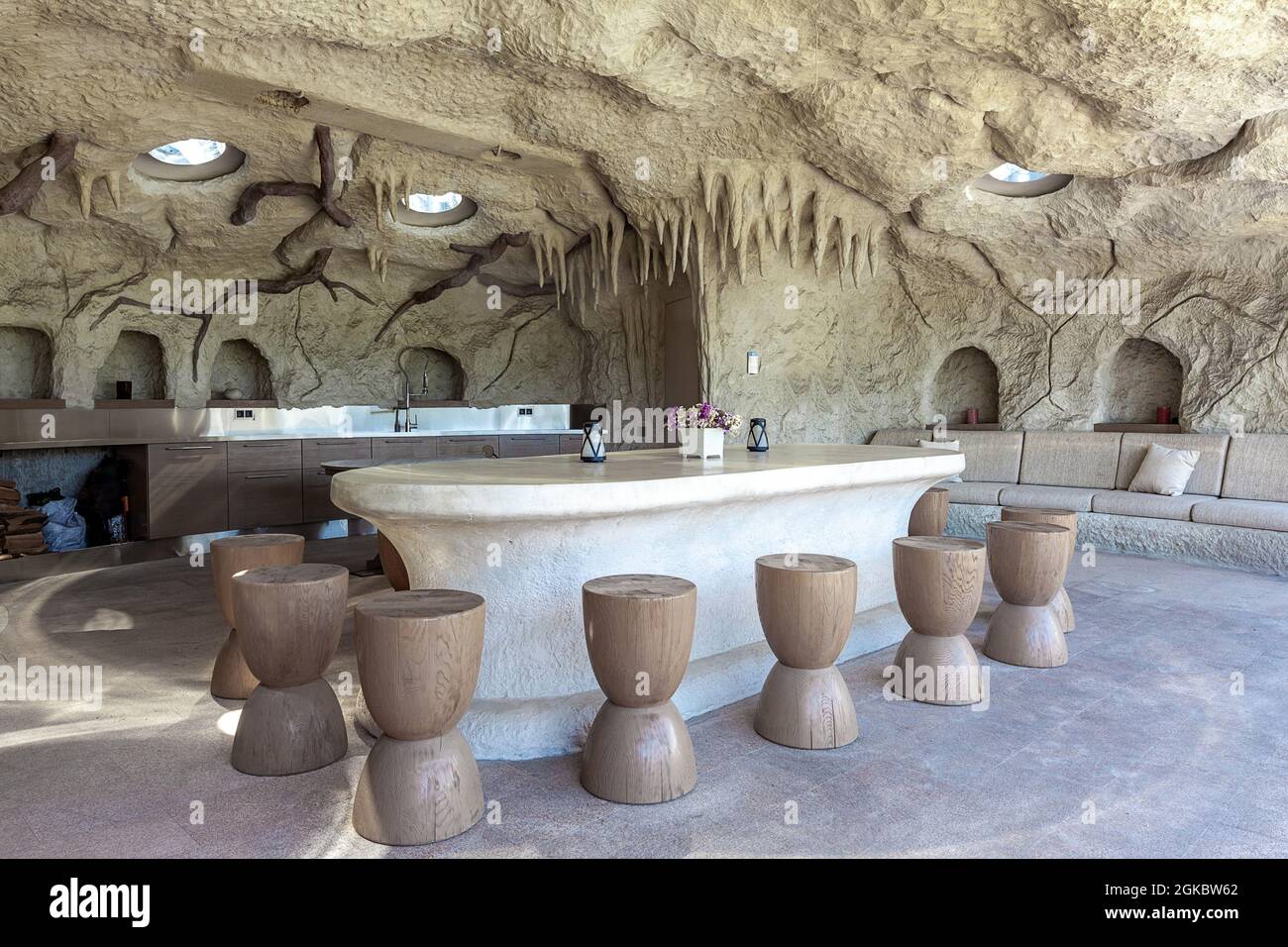 Patio in artificial rocky cave with marble table, wooden chairs, sofa ...